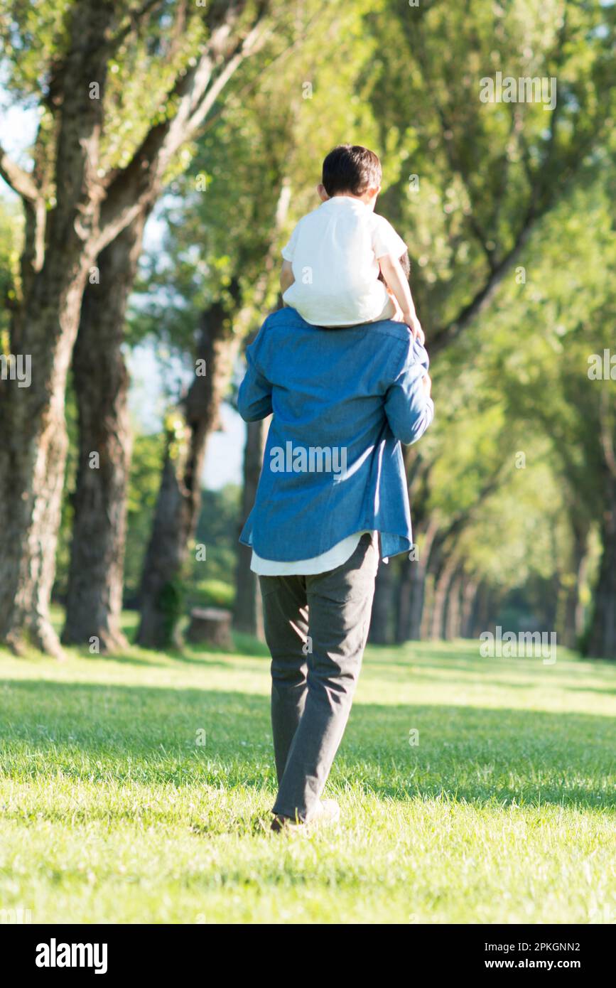 Rear view of a parent and child riding on each other's shoulders in a ...
