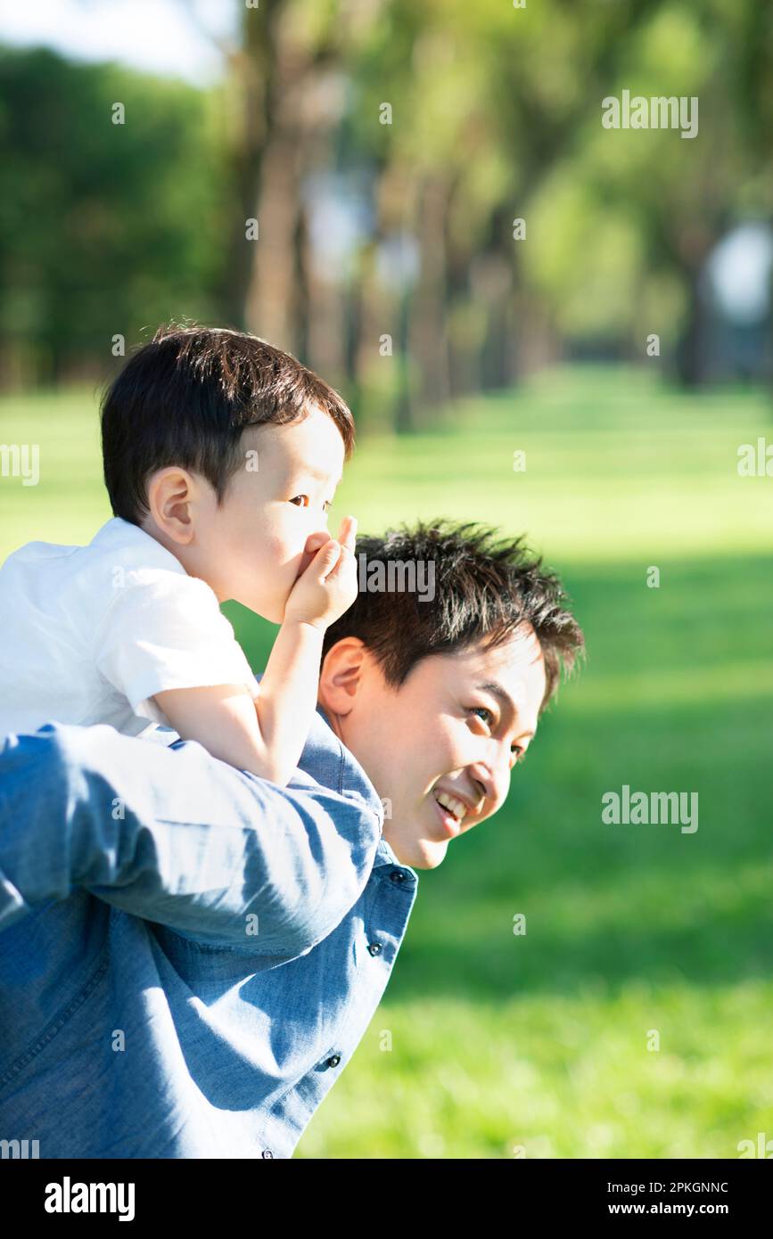 Parent and child carrying a baby on their back at a row of poplar trees ...