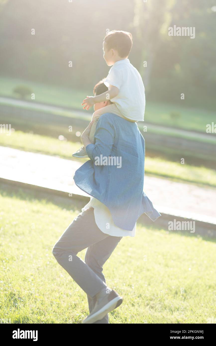 Parent and child riding on each other's shoulders at a park Stock Photo ...