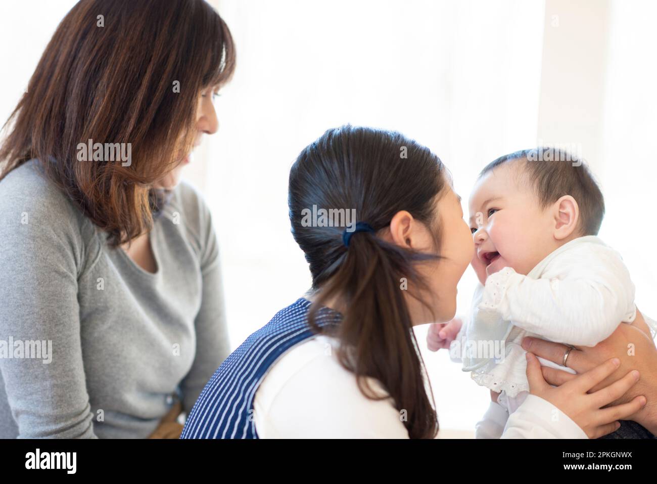 Sisters smiling at each other and mother looking on Stock Photo - Alamy
