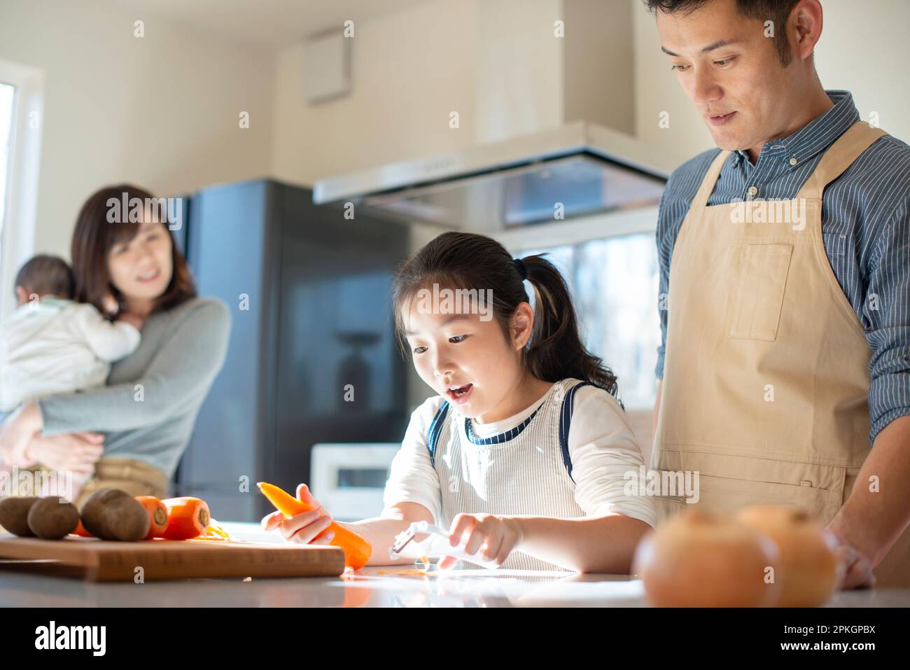 A mother watches her family cooking in the kitchen Stock Photo - Alamy