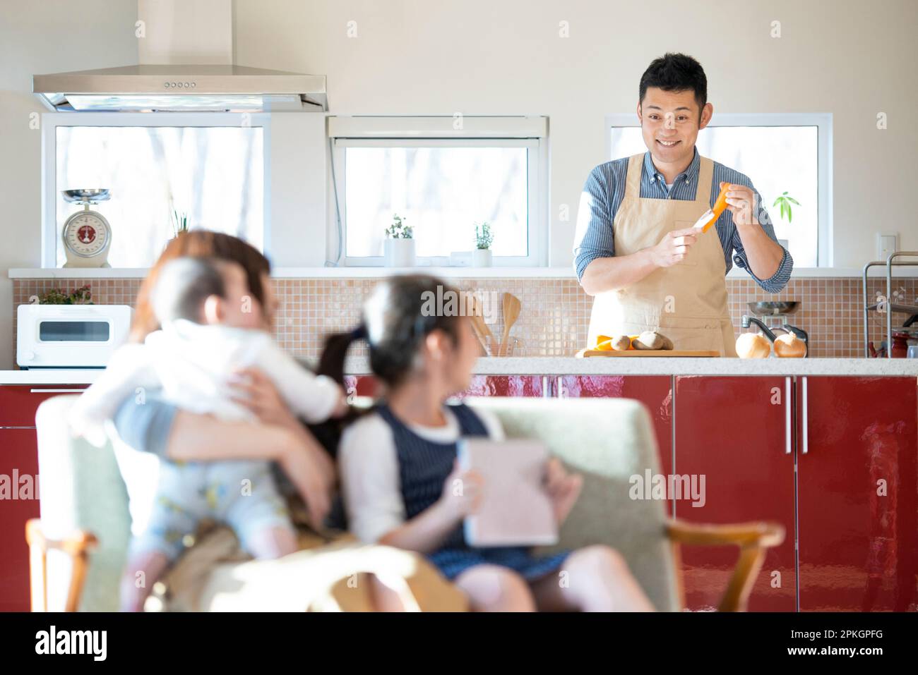 Father cooking in the kitchen with his family watching Stock Photo - Alamy