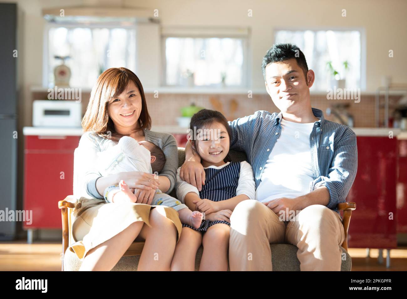 Family sitting on the sofa and smiling Stock Photo - Alamy