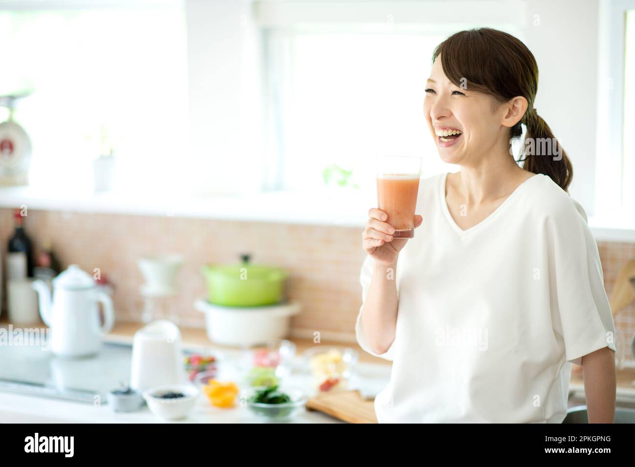 Woman Holding Smoothie And Smiling In Kitchen Stock Photo - Alamy