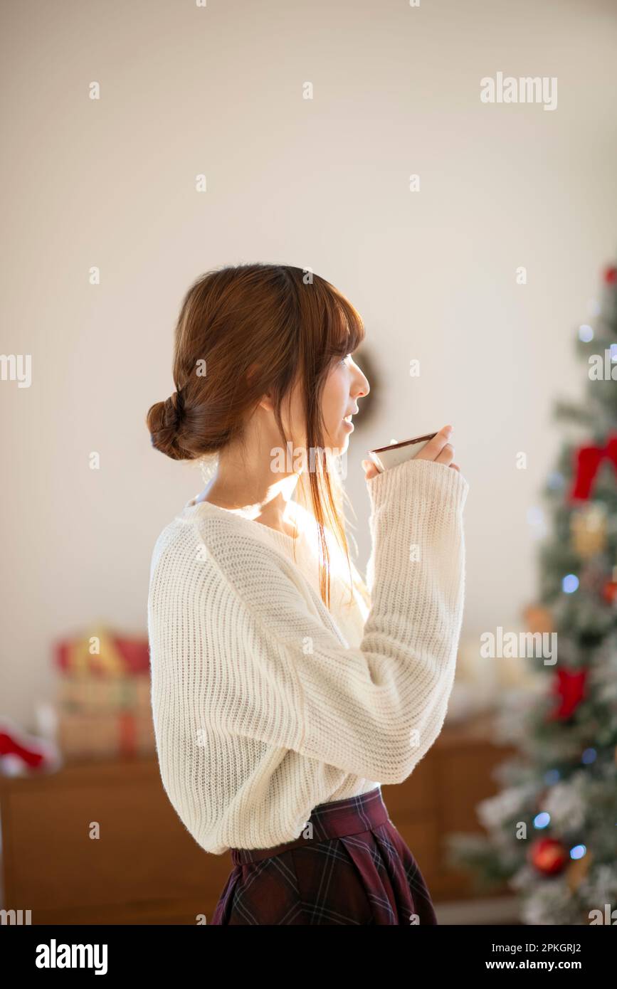 Side view of a woman drinking a drink in front of a tree Stock Photo ...