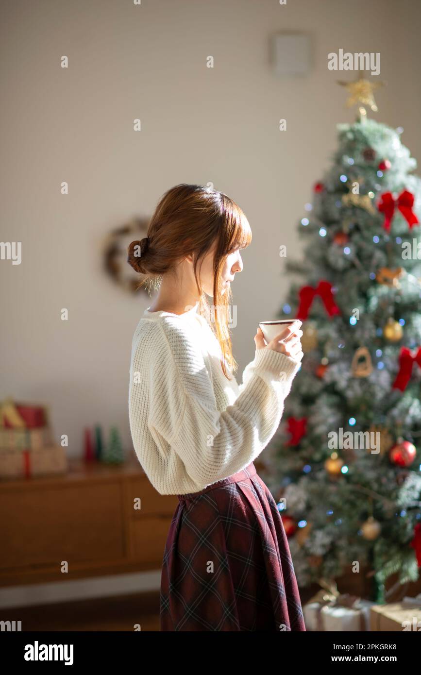 Side view of woman drinking in front of tree Stock Photo - Alamy