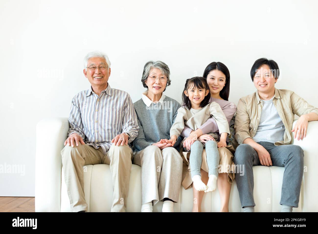 Family of three generations sitting and smiling on the sofa Stock Photo ...
