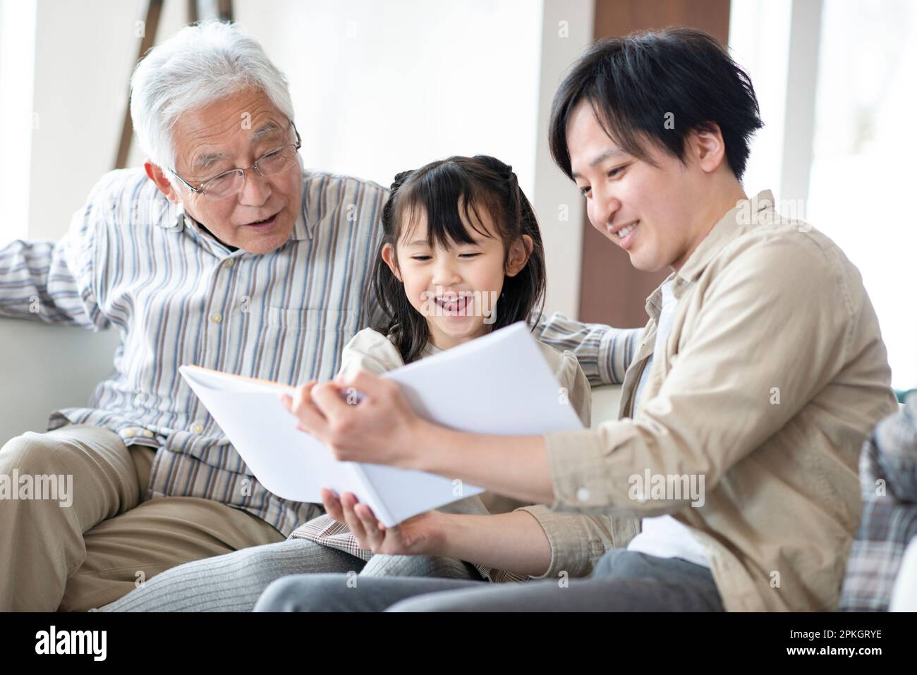 Family of 3 generations reading a picture book Stock Photo - Alamy