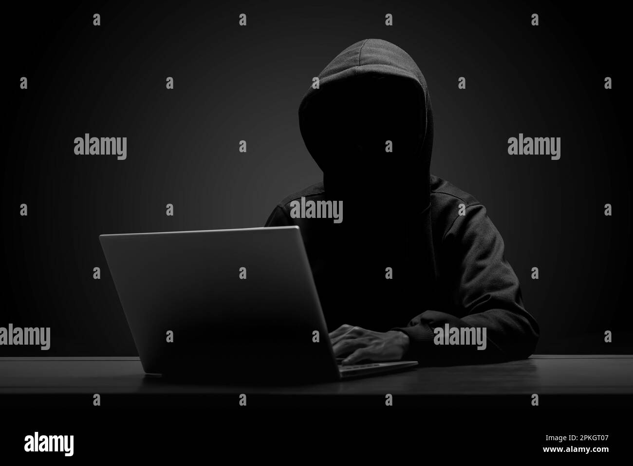 Mysterious man wearing black hoodie using laptop in the dark room ...