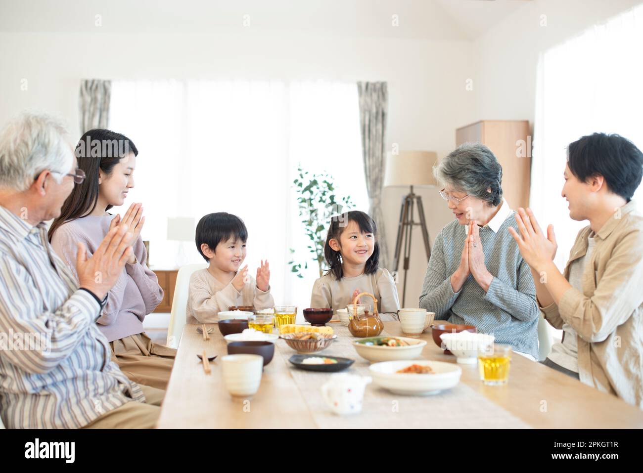 A family of three generations holding hands before eating a meal Stock ...