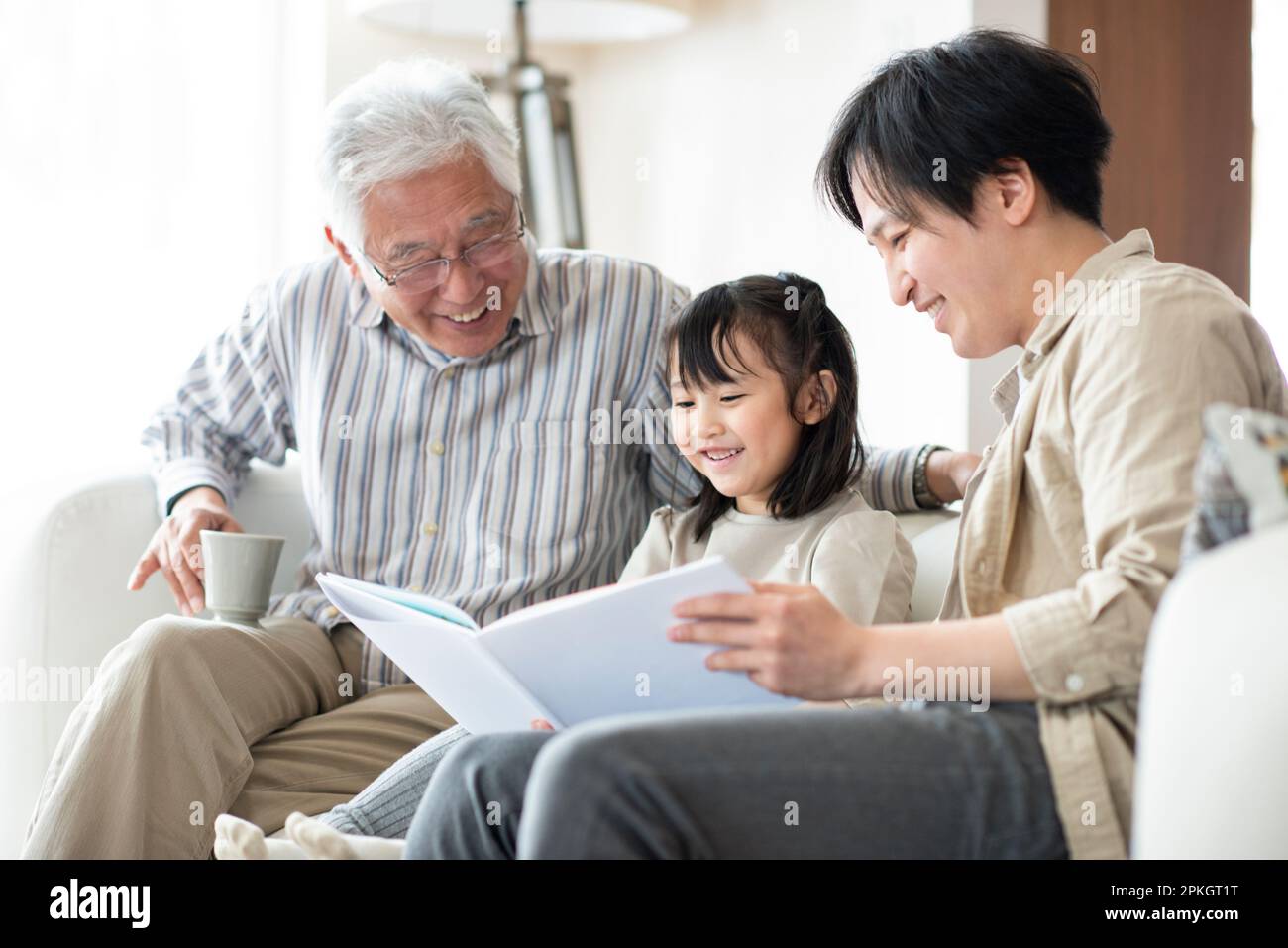 Family of 3 generations reading a picture book Stock Photo - Alamy