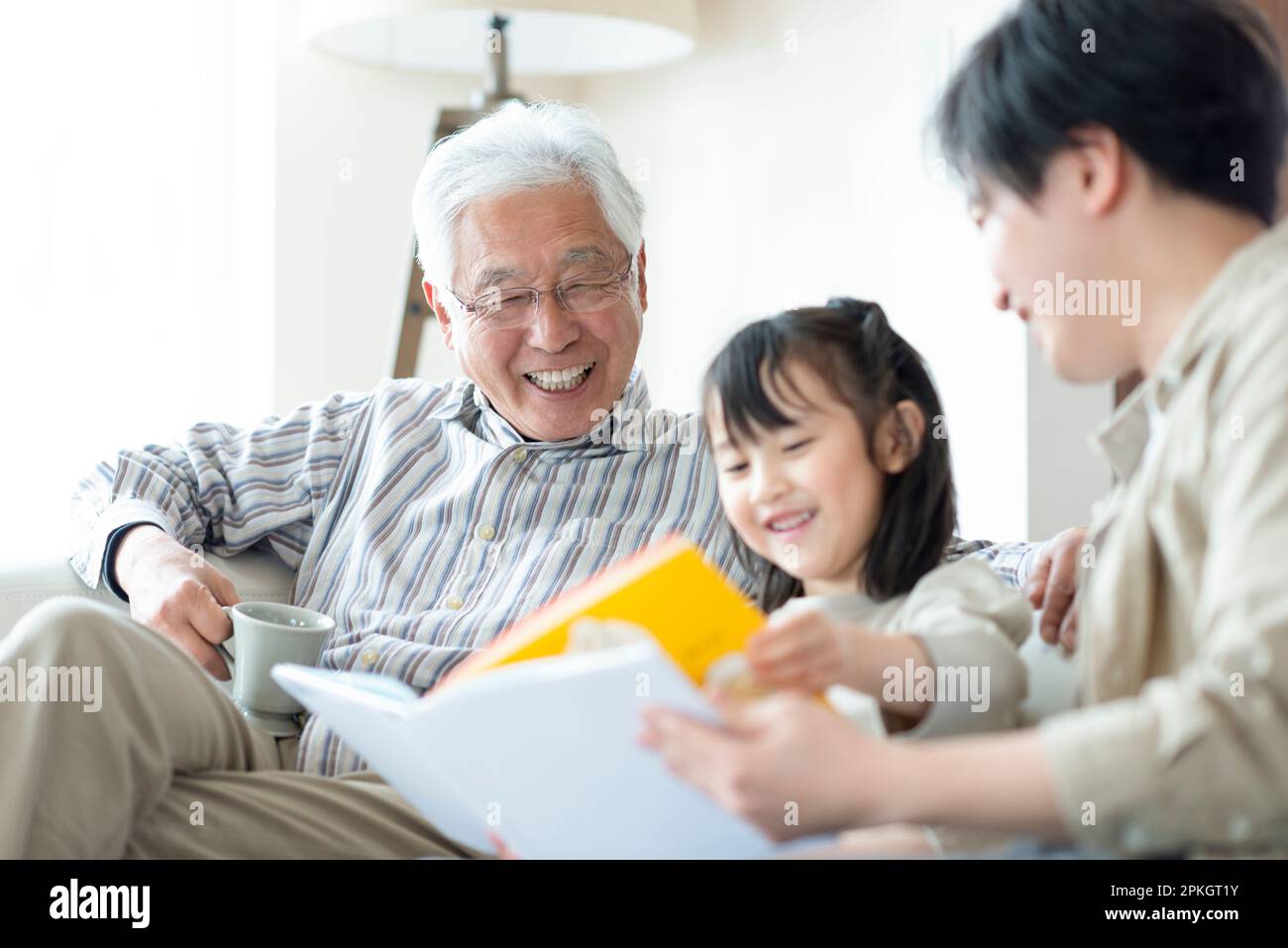 A family of 3 generations reading a picture book Stock Photo - Alamy