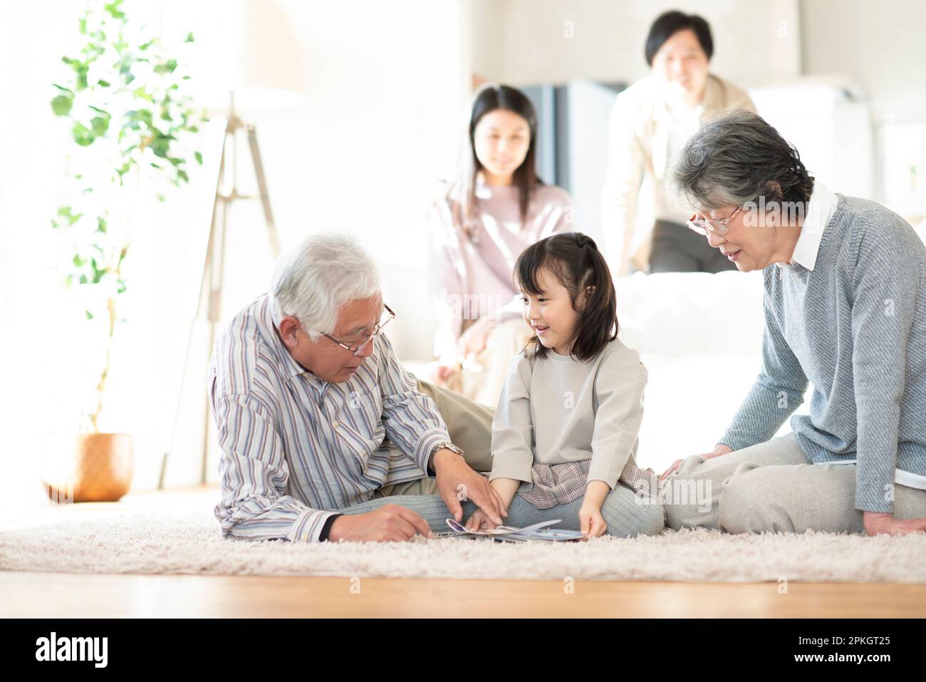A three-generation family reading a picture book Stock Photo - Alamy