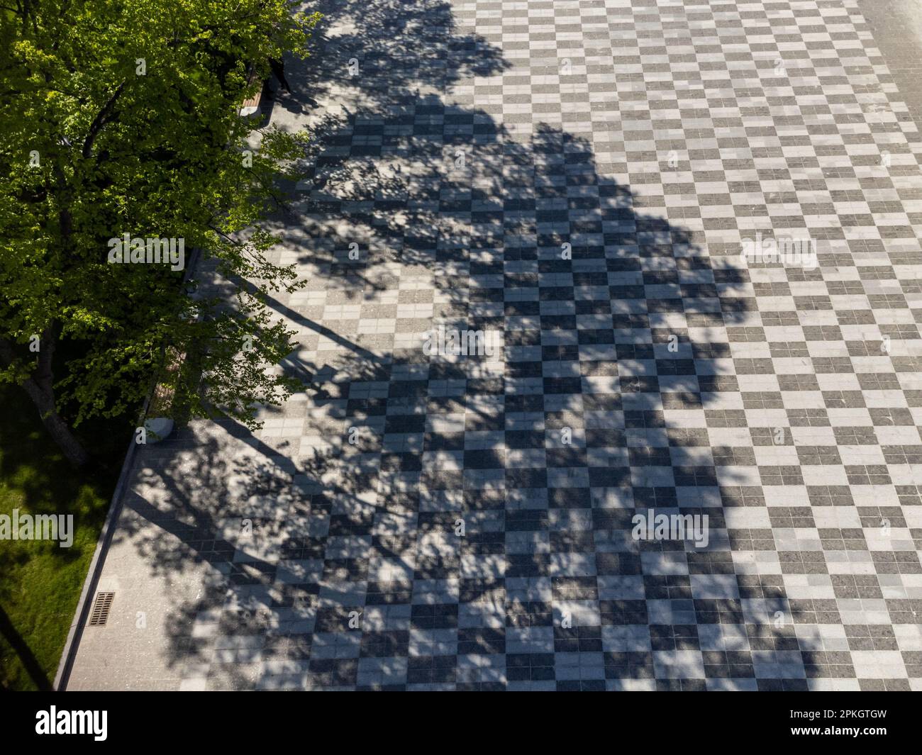 Look down aerial view on tiled walking street, cobbled square with dark ...