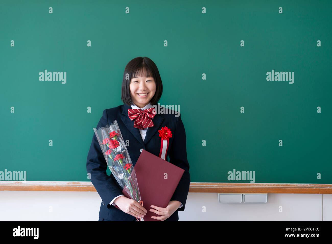 A female student holding her diploma and flowers and smiling Stock ...