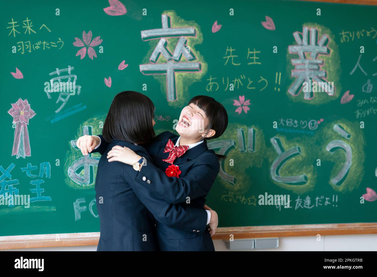 Female students hugging each other in front of the blackboard Stock ...