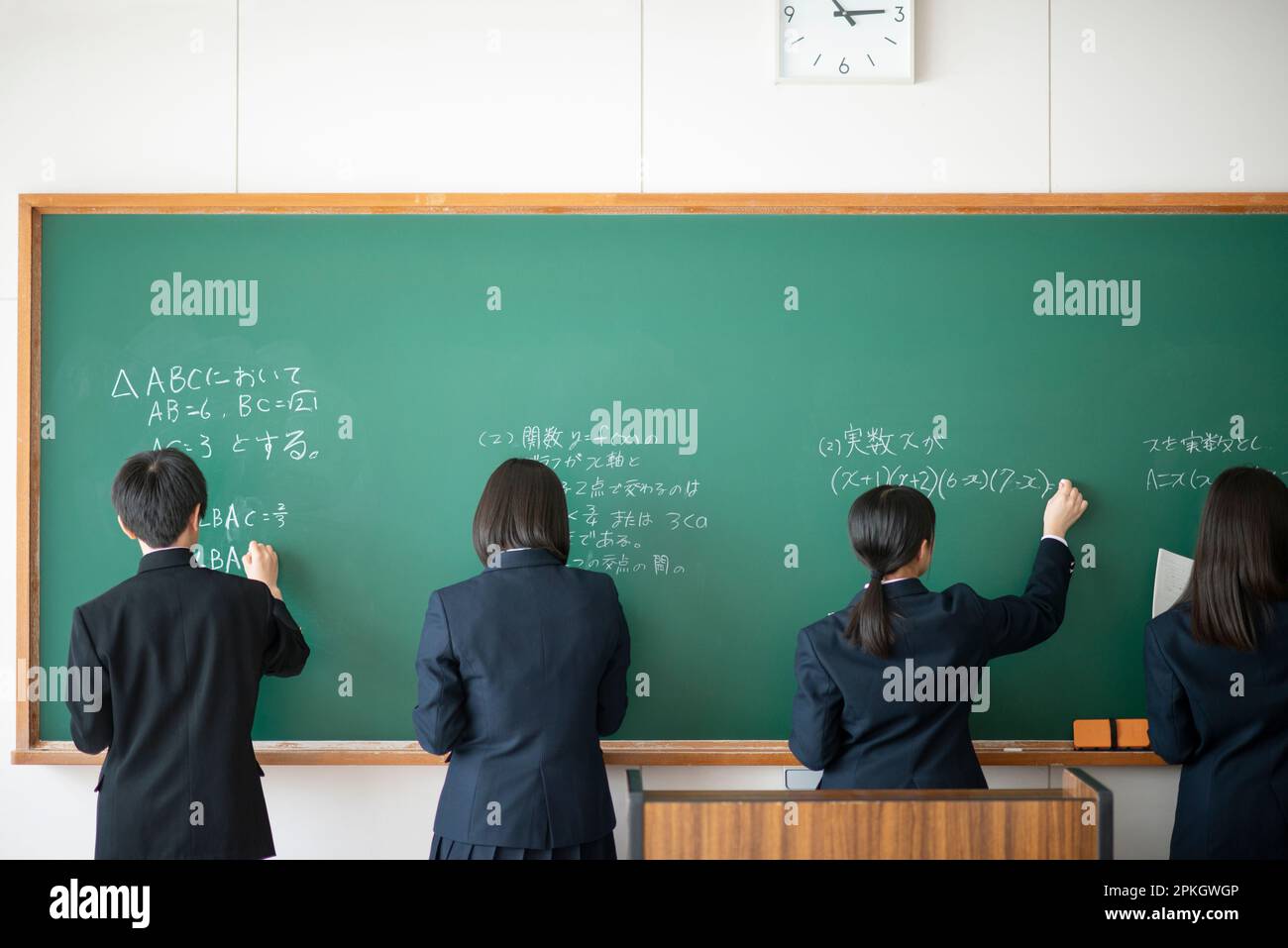 Back view of a student writing answers on the blackboard with chalk ...