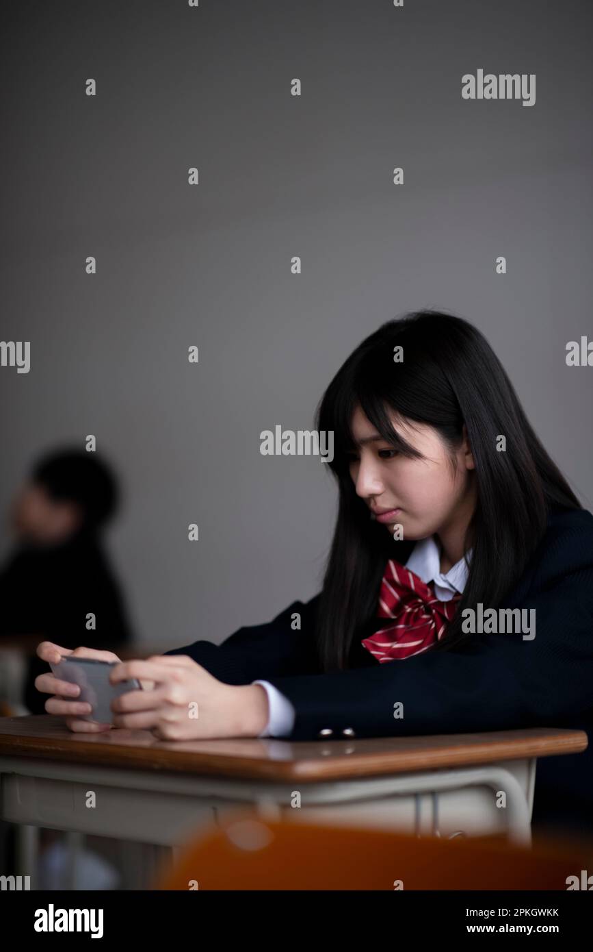 Female student looking at her smartphone in a classroom Stock Photo - Alamy