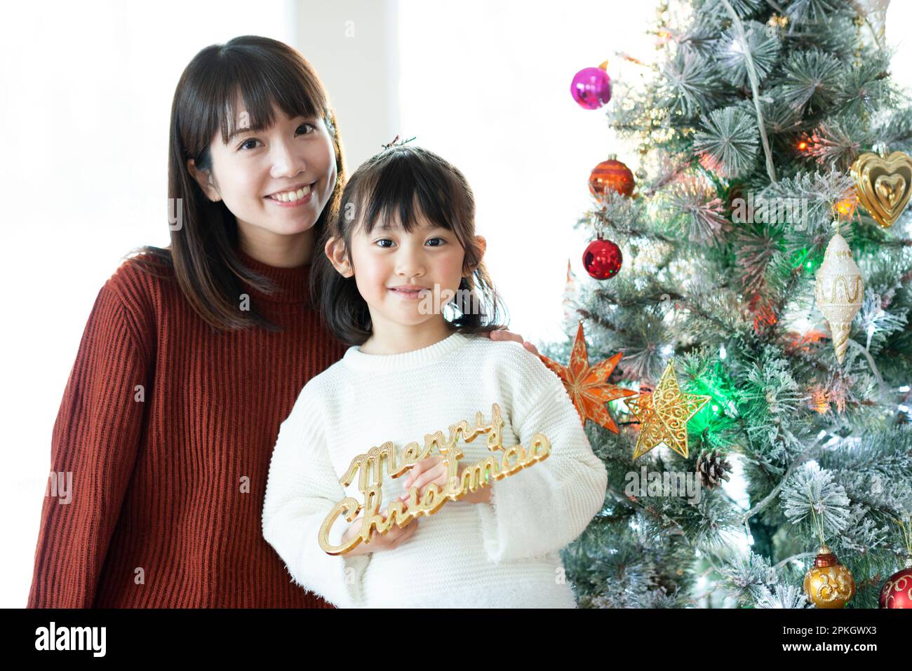 Parent and child smiling in front of the Christmas tree Stock Photo - Alamy