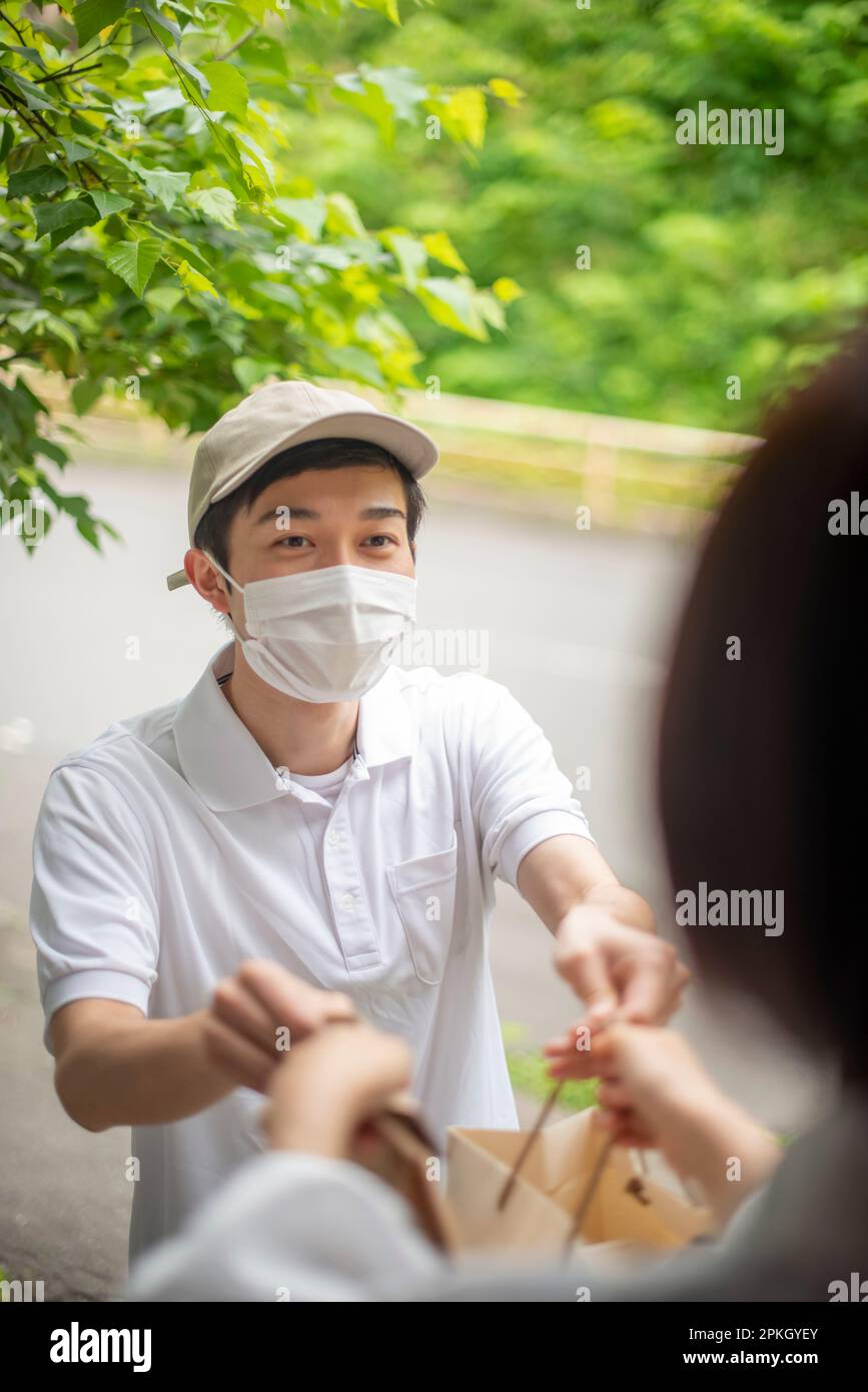Delivery man handing a paper bag at the front door Stock Photo - Alamy