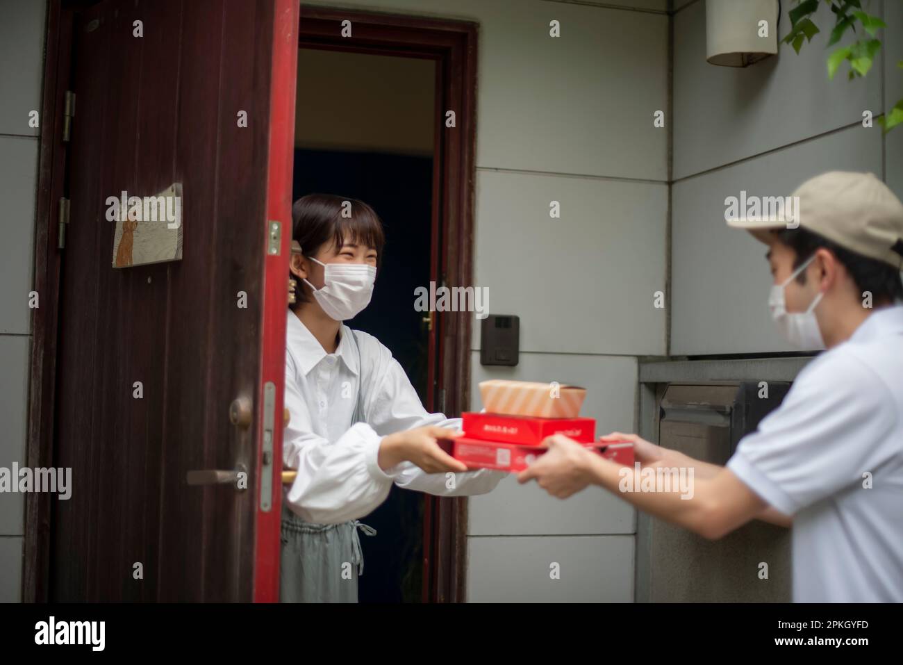 Woman receiving delivery at the front door Stock Photo - Alamy