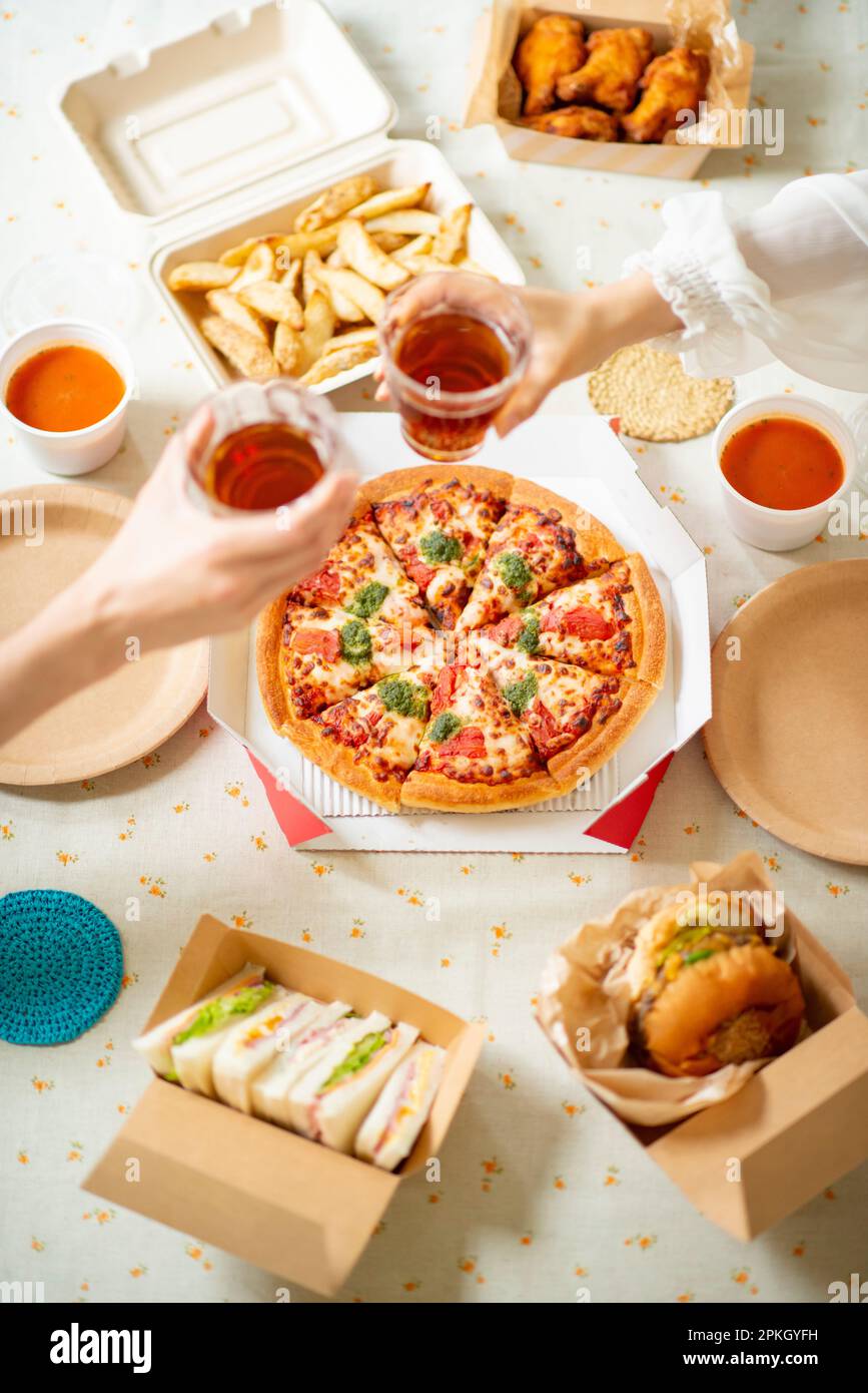 Couple making a toast at a table lined with takeout Stock Photo - Alamy