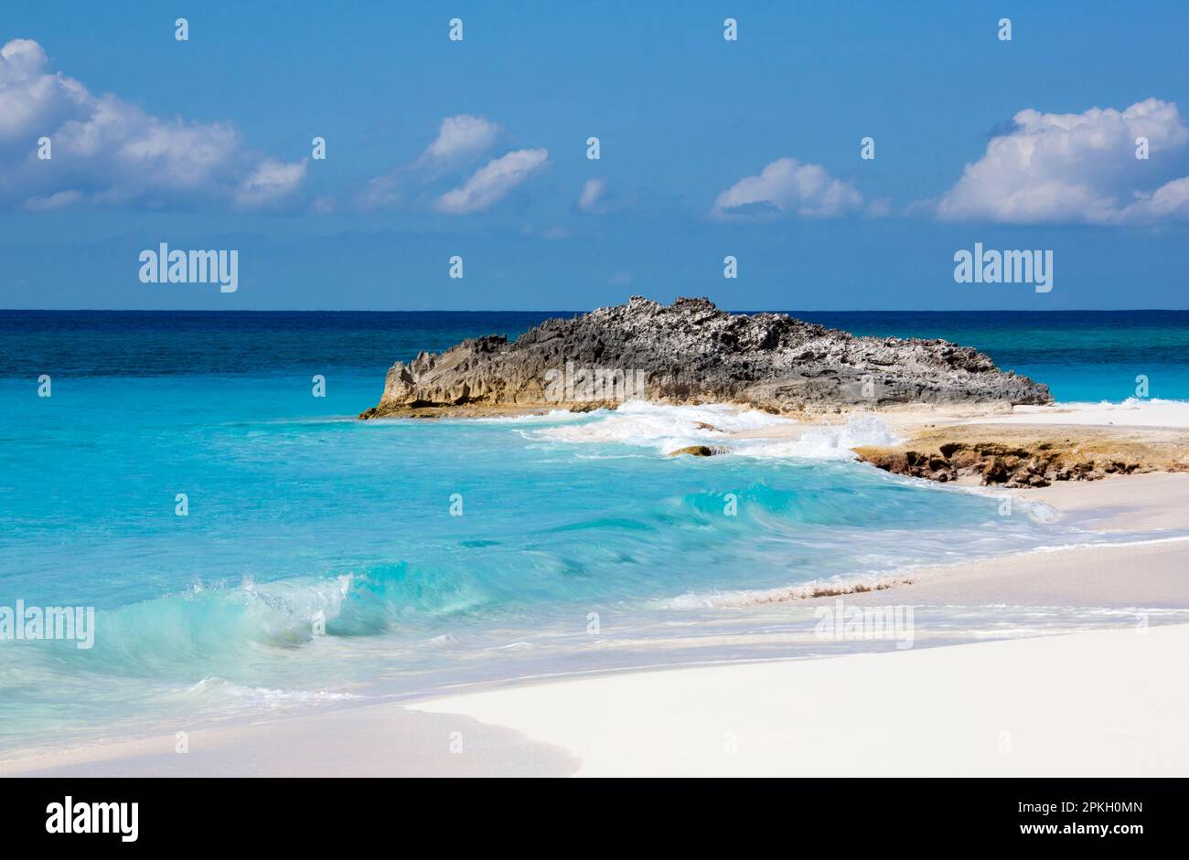 The scenic view of turquoise color waves a sandy beach rock in a ...