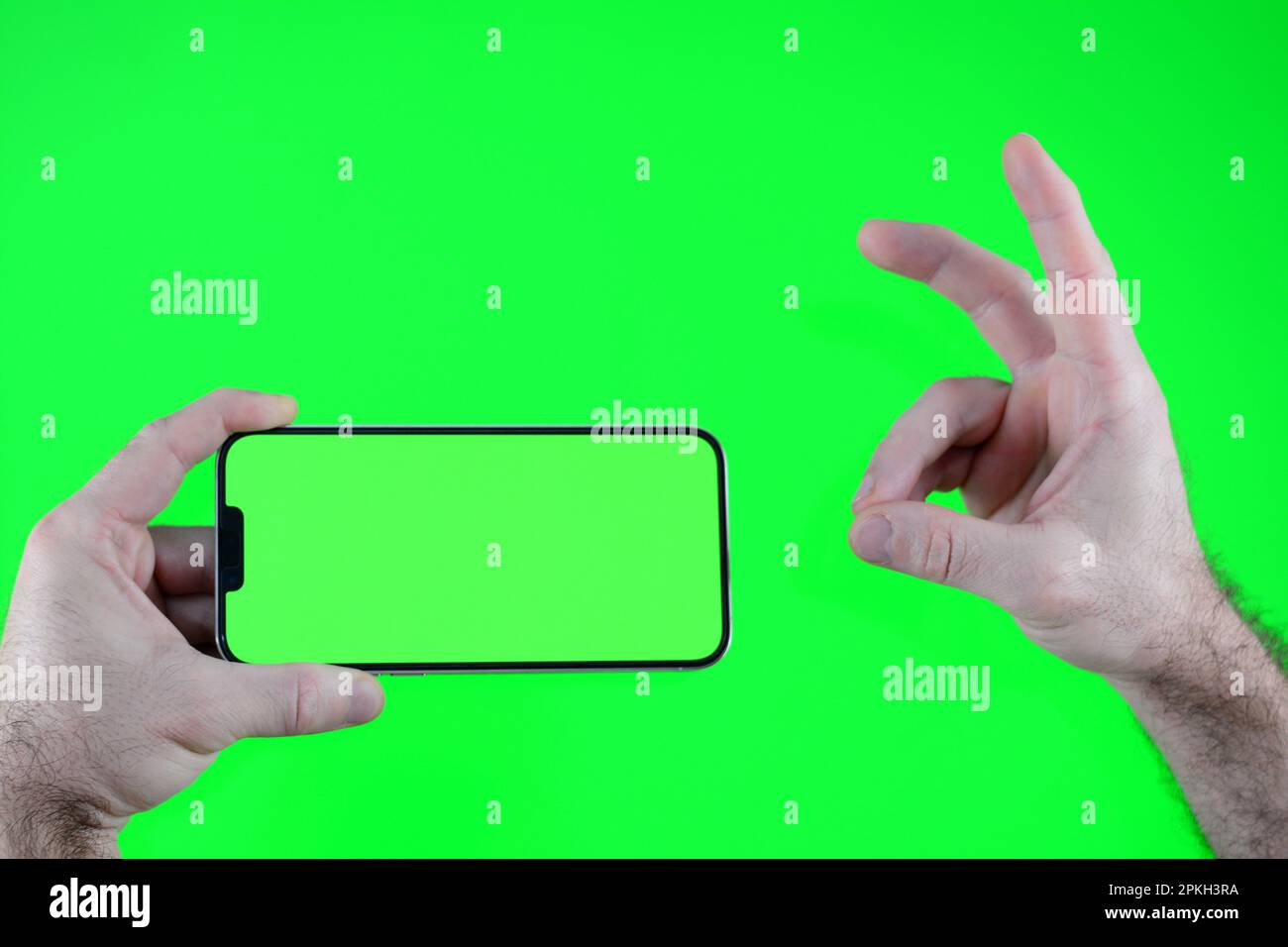 Man's hand shows mobile smartphone with green screen in vertical ...