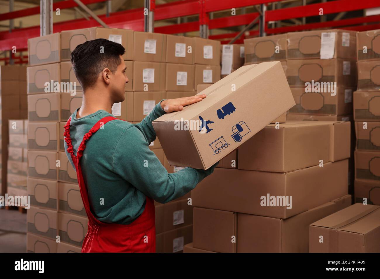 Worker stacking cardboard boxes with shipping icons in warehouse ...