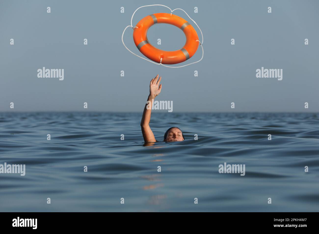 Drowning woman with raised hand getting lifebelt in sea Stock Photo - Alamy