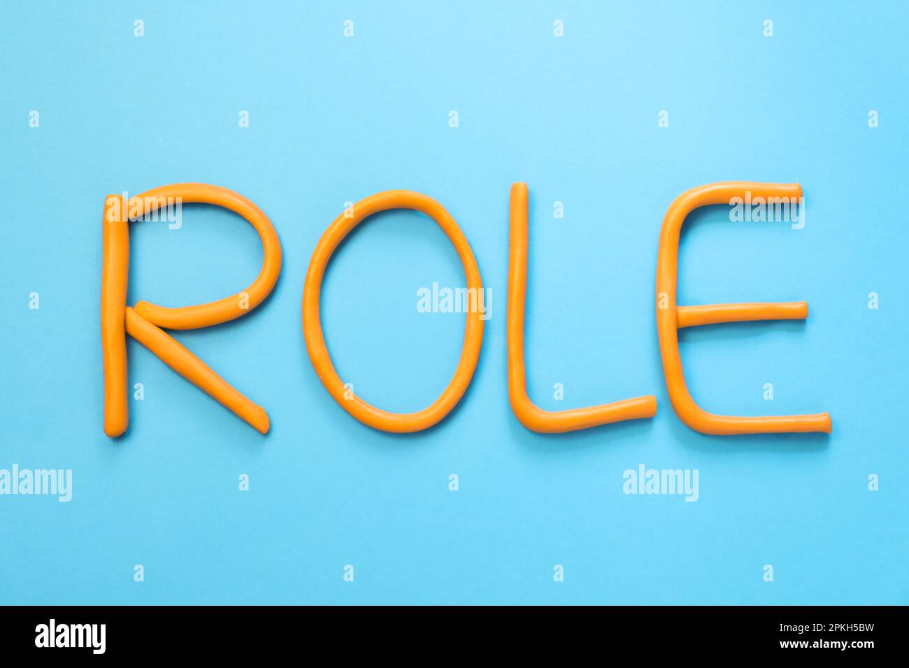 Word Role made with orange plasticine on light blue background, flat ...