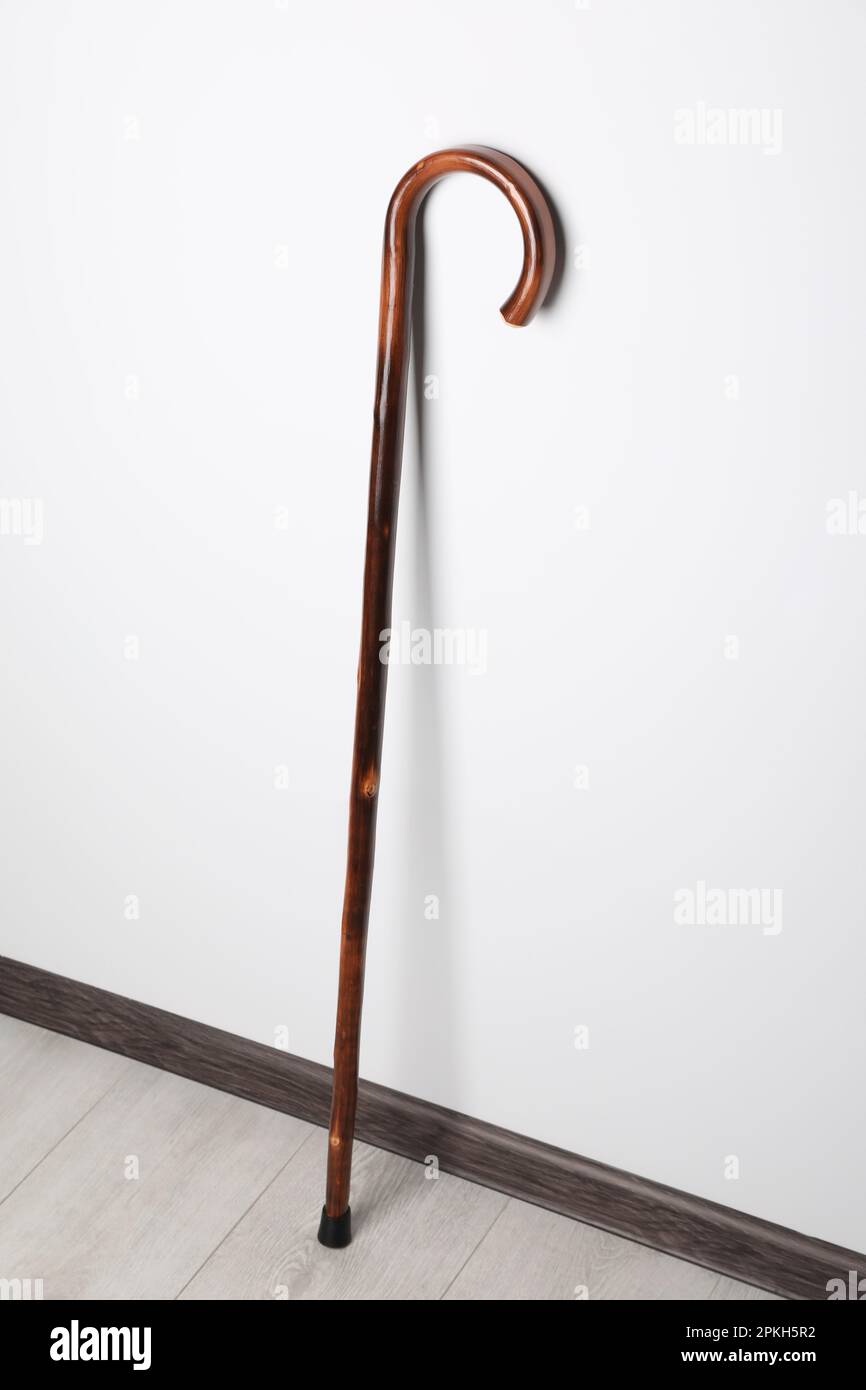 Elegant wooden walking cane near white wall indoors Stock Photo - Alamy