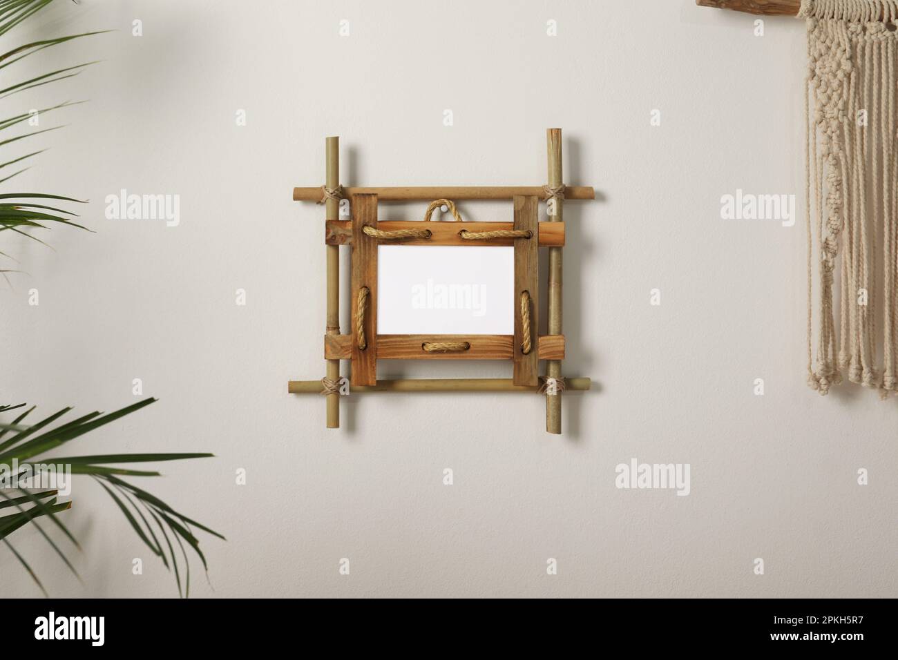 Empty bamboo frame hanging on white wall indoors Stock Photo - Alamy