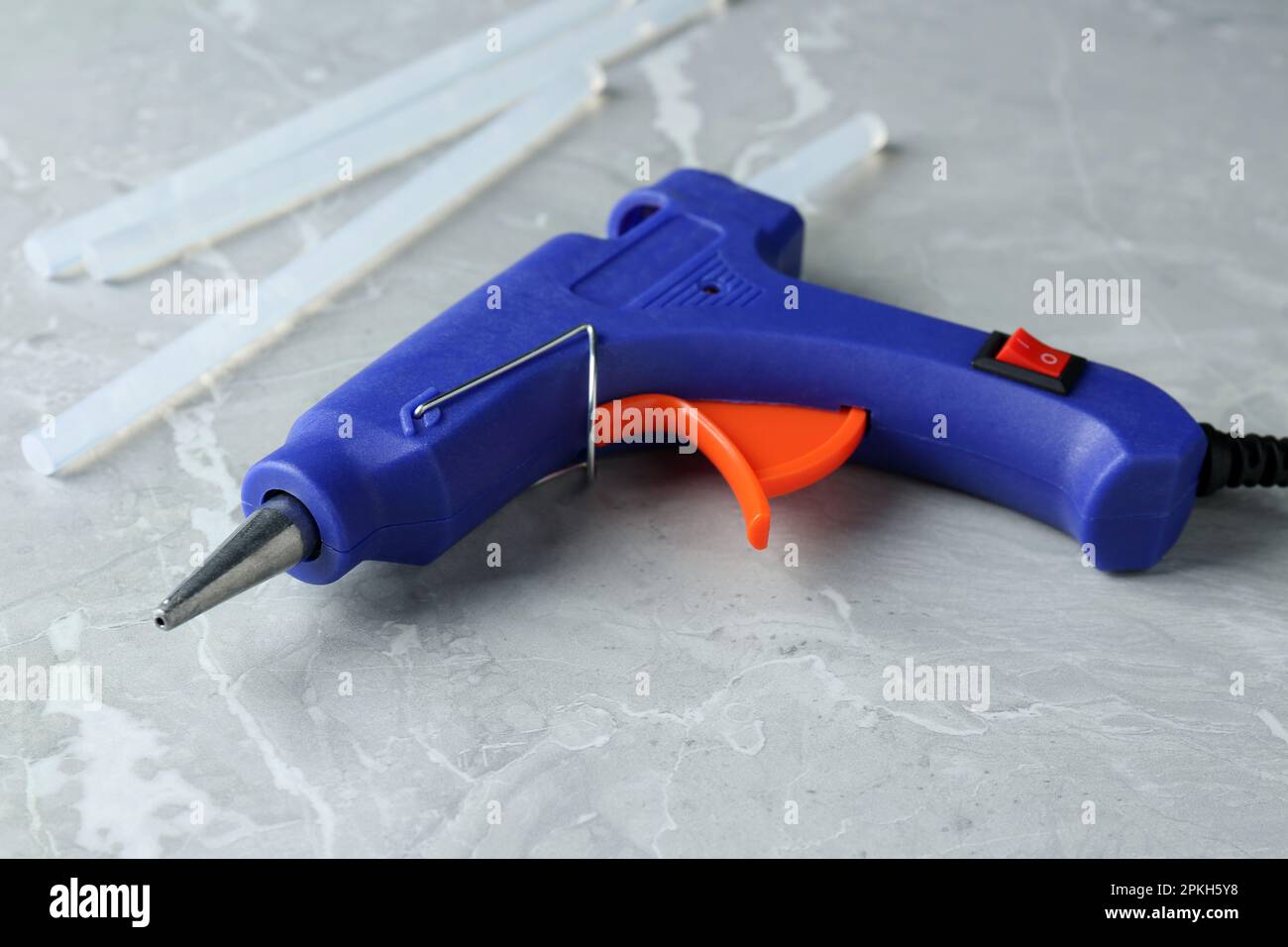 Hot glue gun and sticks on light grey marble table Stock Photo - Alamy