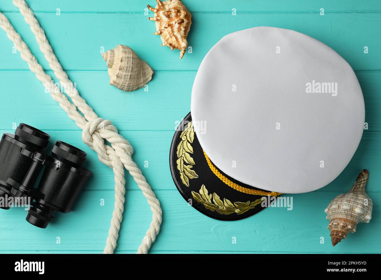 Peaked cap, rope, shells and binoculars on turquoise wooden background ...