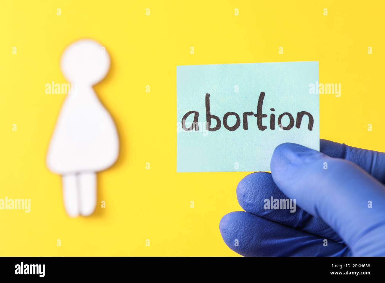 Doctor holding card with word ABORTION and paper cutout of pregnant ...