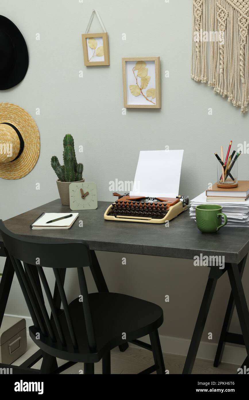 Typewriter and stack of papers on dark table in room. Writer's ...