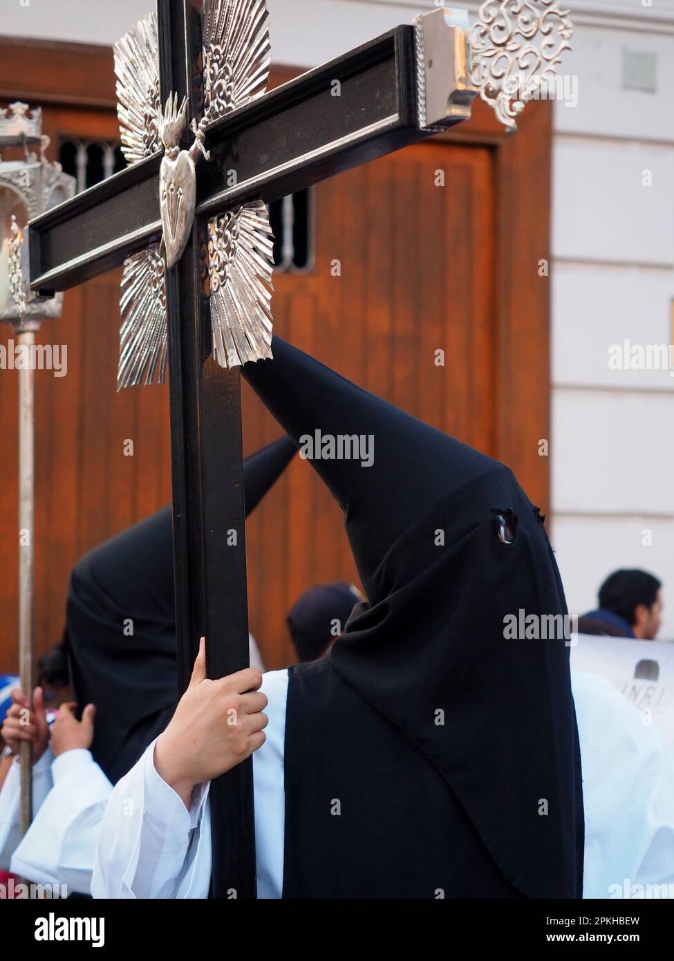 Hooded catholic devotees carrying on a religious procession at eve on ...
