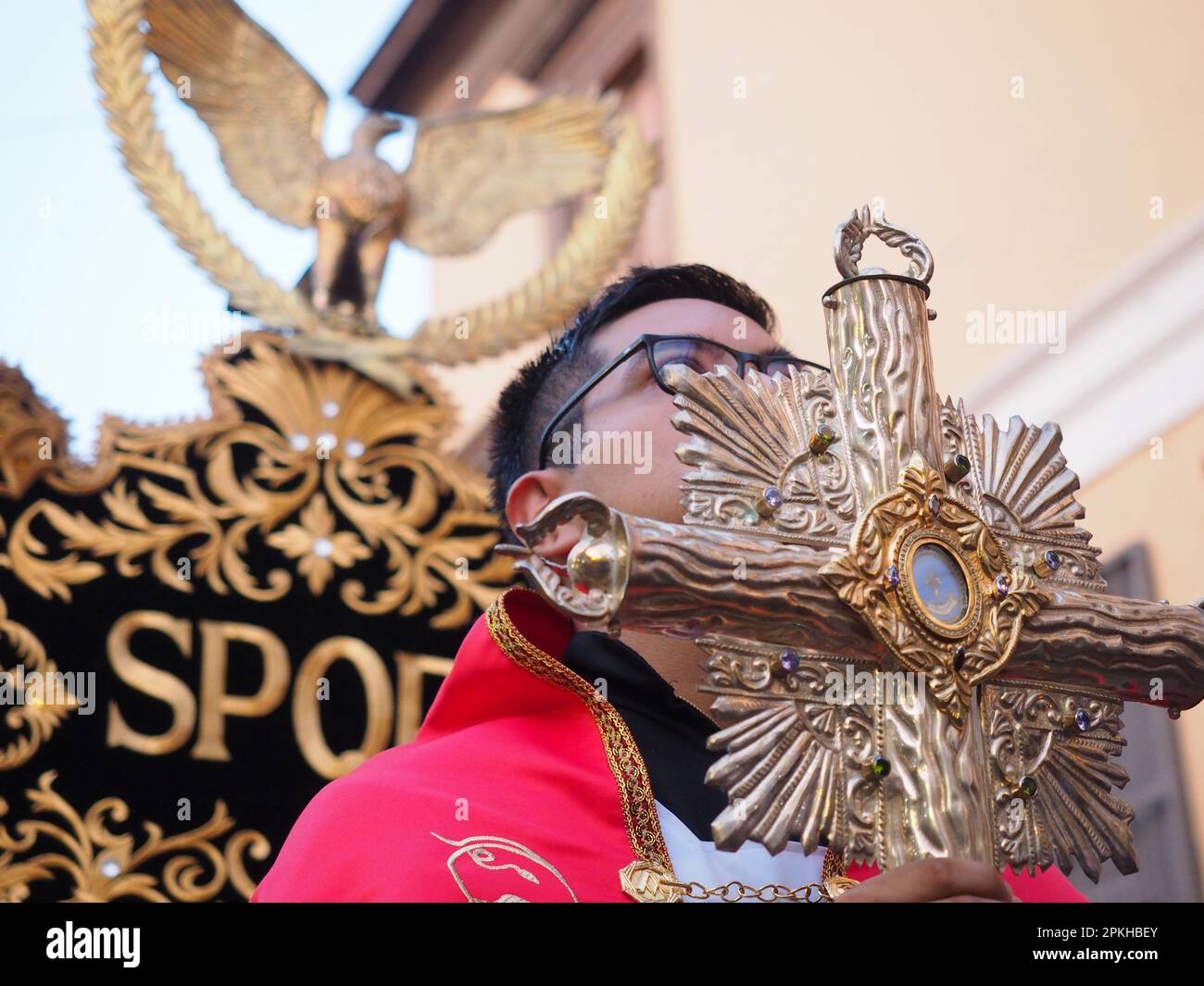 A priest carrying a crucifix on a religious procession at eve on Holy ...