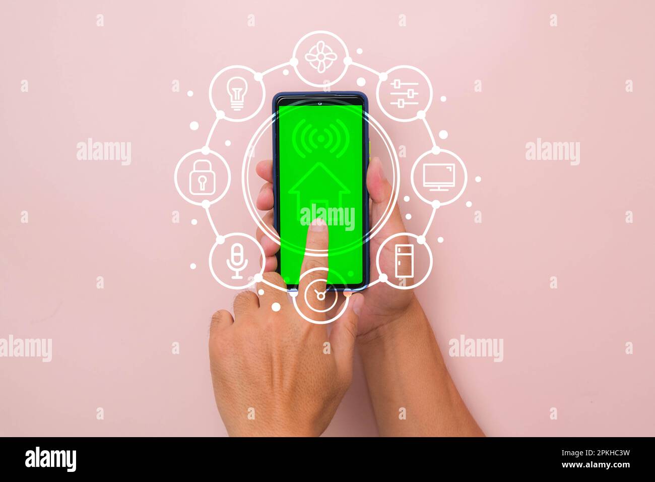 Male hand holding smart phone on pink background with smart home ...