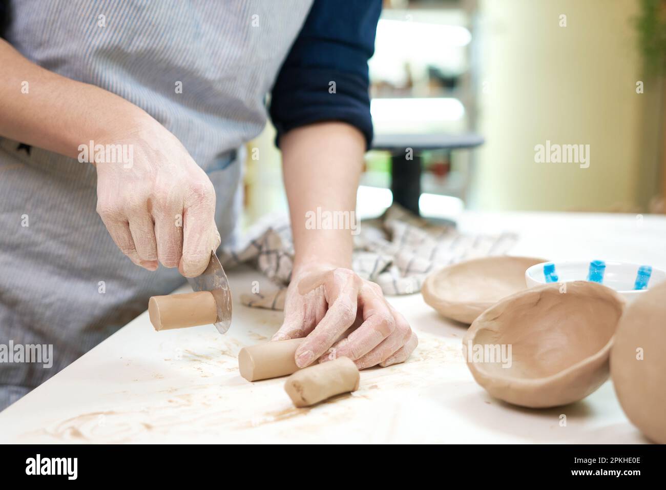 Woman cutting clay with blade standing behind table in studio Stock ...