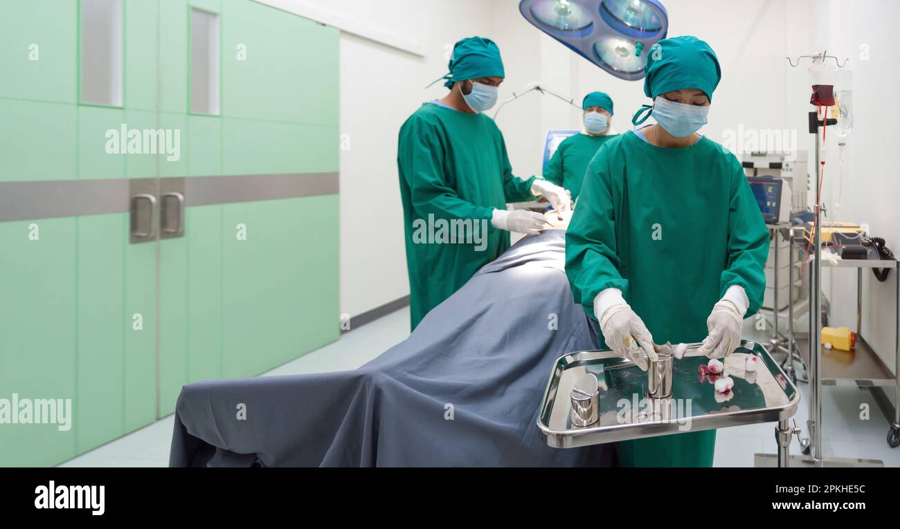 Group of surgeons and nurse in surgical green gown uniform performing ...