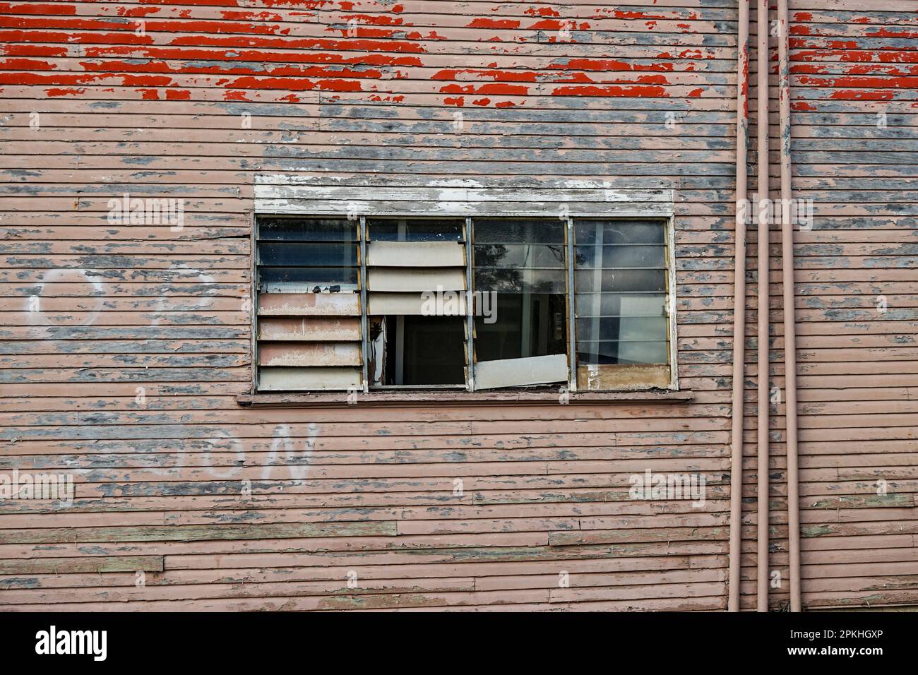 Louvred windows with missing panes in the centre of an old weatherboard ...