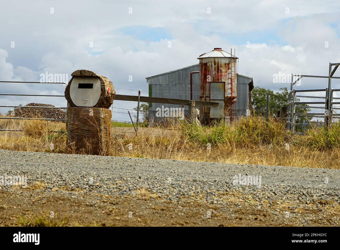 Rustic mail box beside gravel road, with fence, gate, silo and iron ...