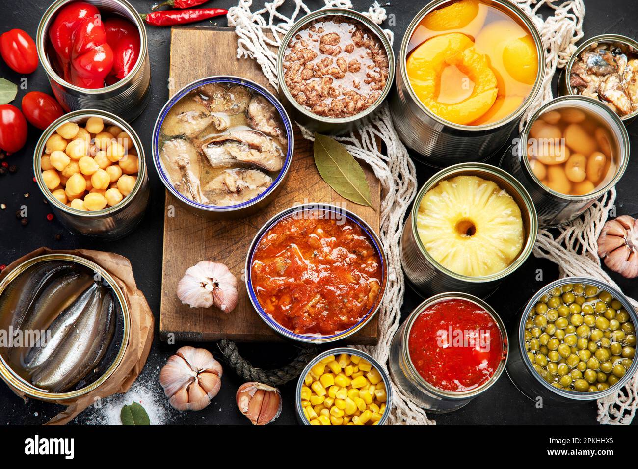 Various canned vegetables, meat, fish and fruits in tin cans. On a dark ...