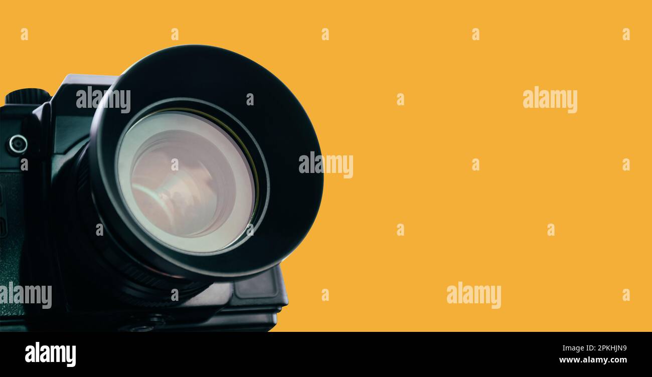 Front lens of vintage film camera with black body isolated on yellow ...