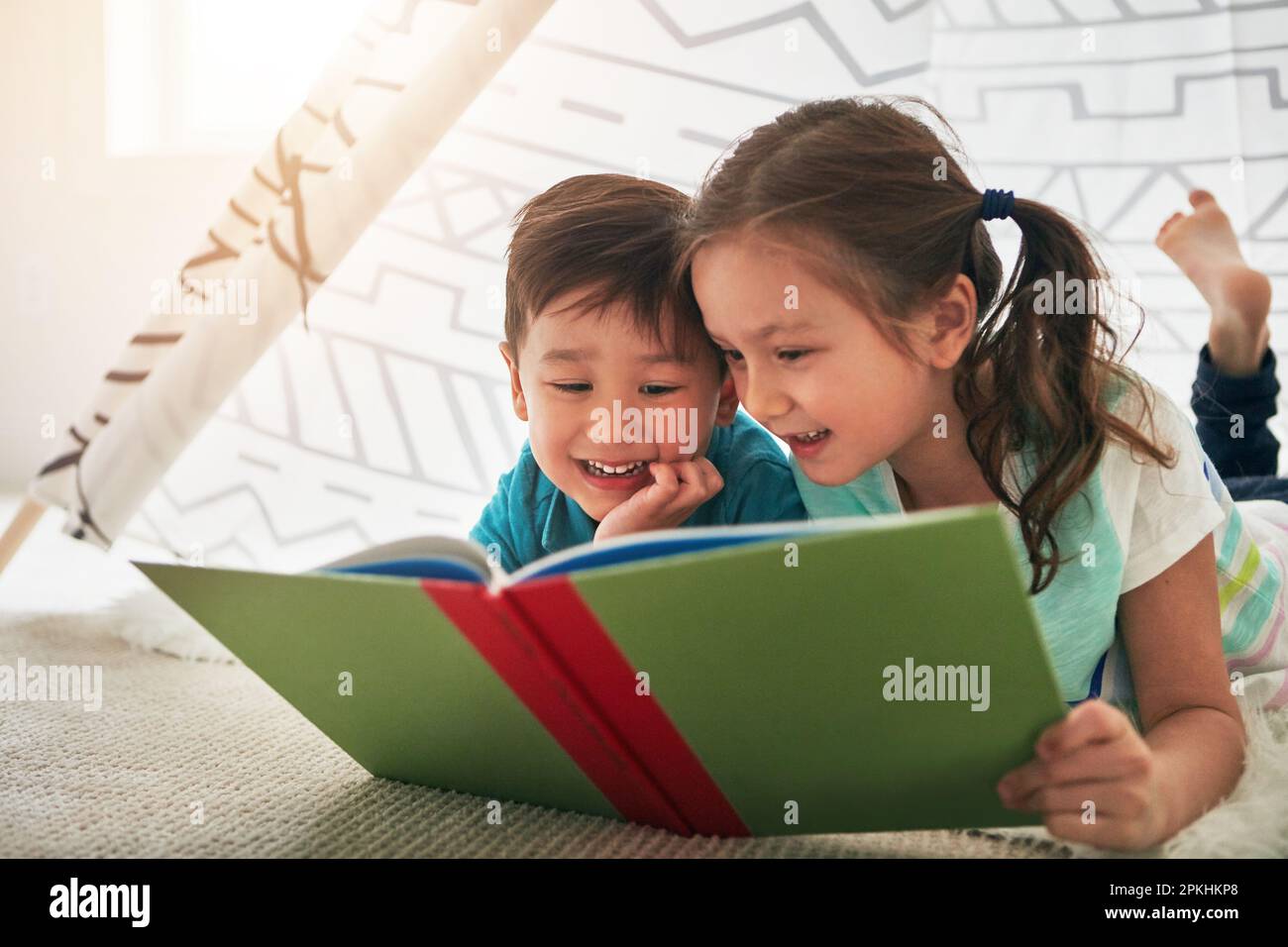 Becoming keen readers. two adorable young siblings reading a book ...