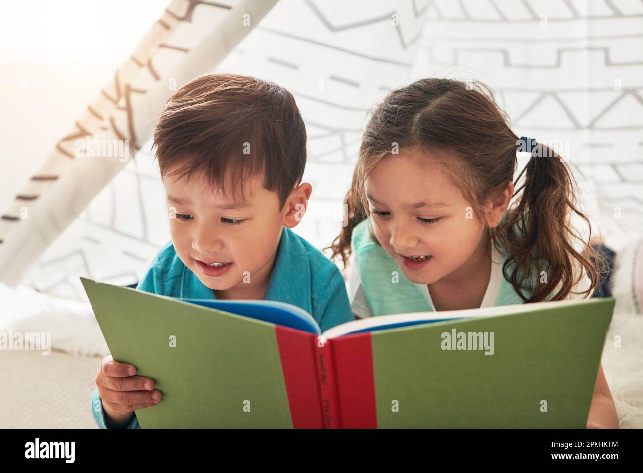 Learning to read together. two adorable young siblings reading a book ...