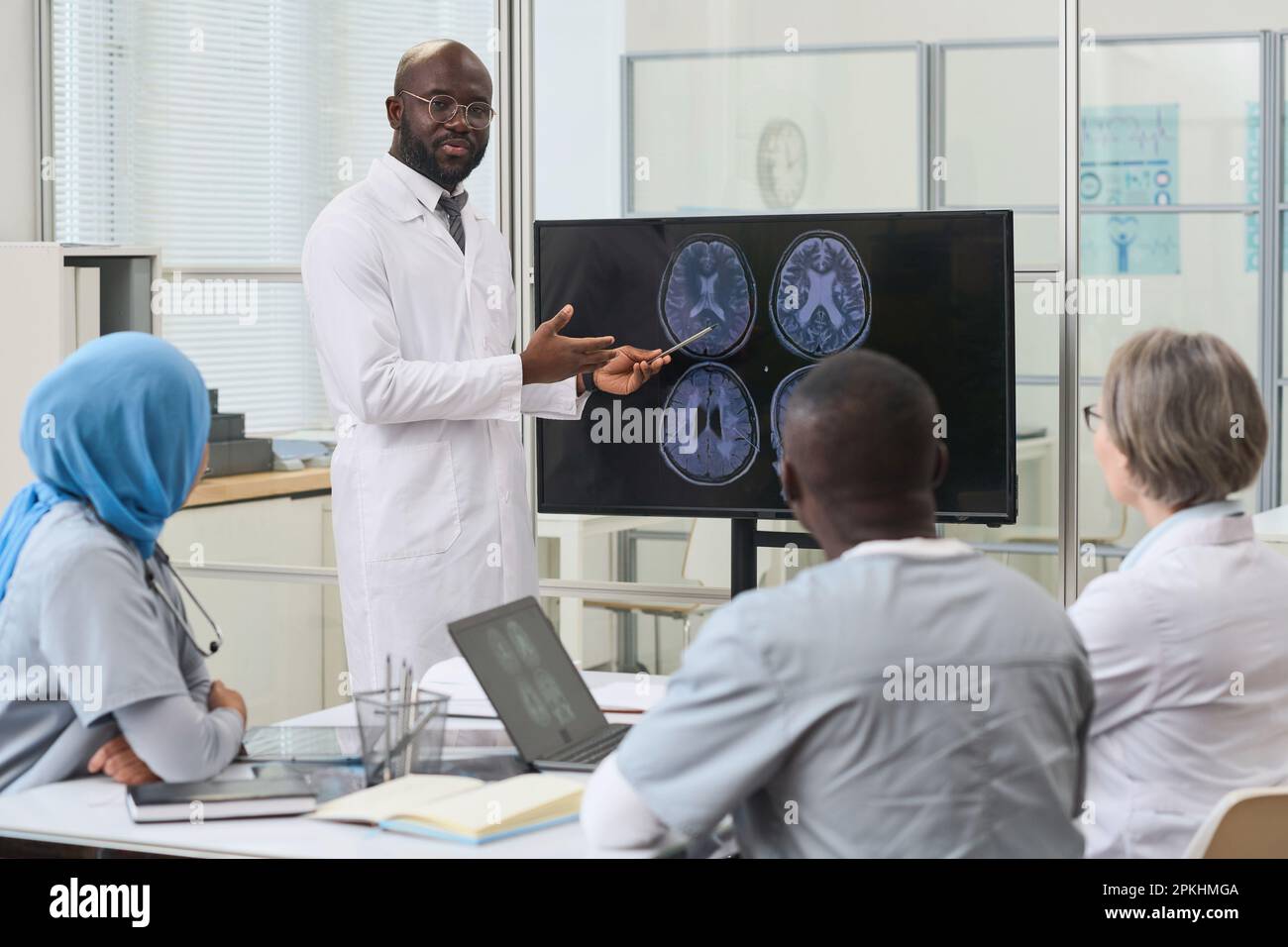 African American doctor in white coat presenting x-ray image on monitor ...