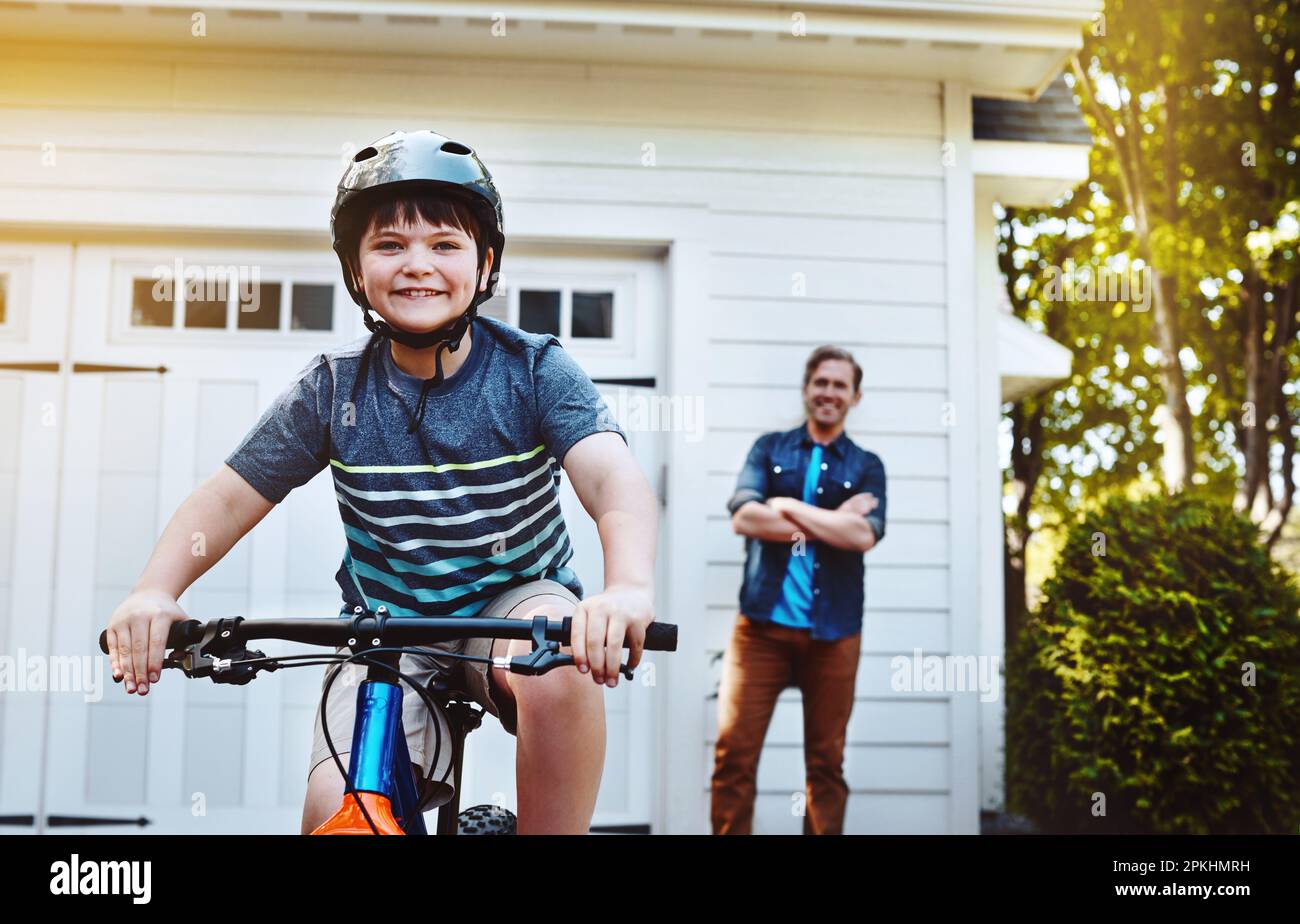My Dad taught me how to ride. a young boy riding a bicycle with his father in the background ...